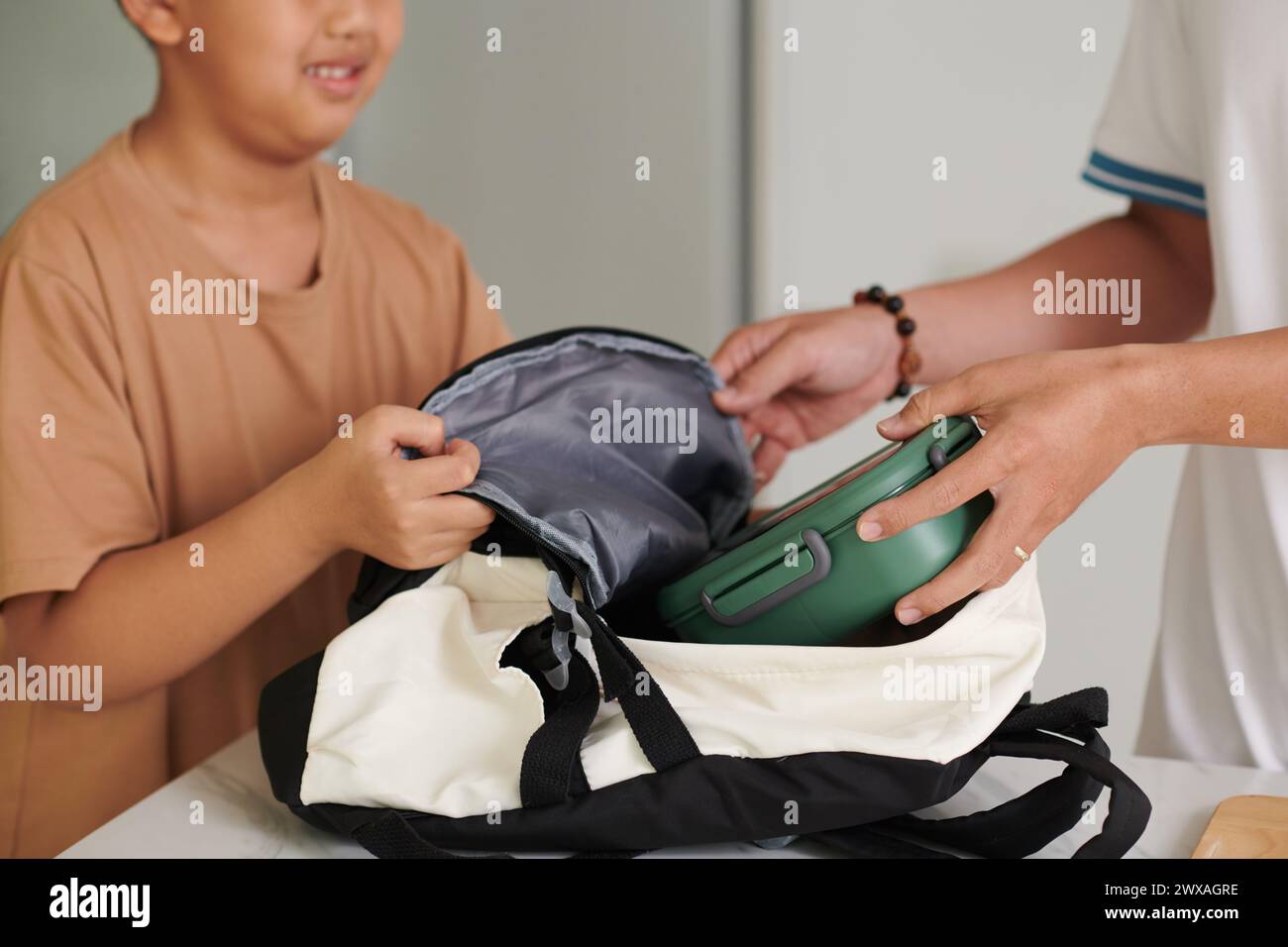 Caring father putting lunch box in school bag of preteen son Stock ...
