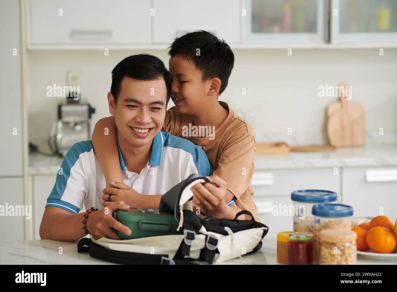 Happy son hugging father packing his lunch bag Stock Photo - Alamy