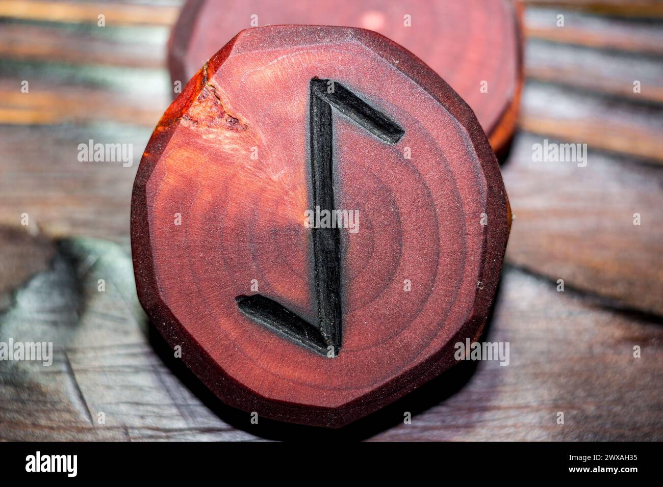 Rune Eihwaz (Eihaz) red color carved from wood on a wooden background ...