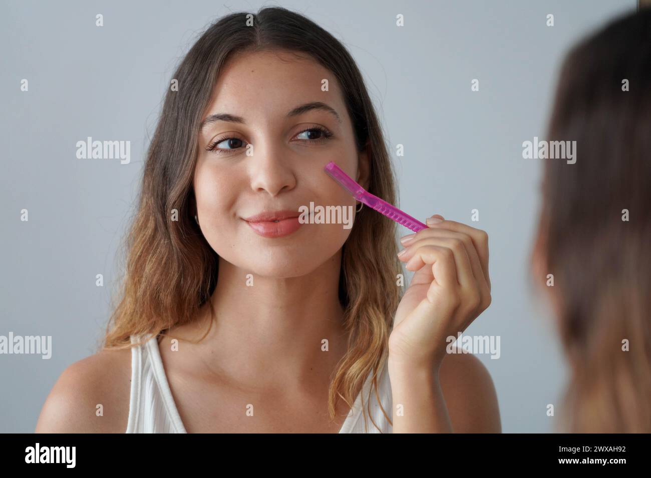 Facial hair removal. Dermaplaning. Close-up of beautiful girl shaving ...