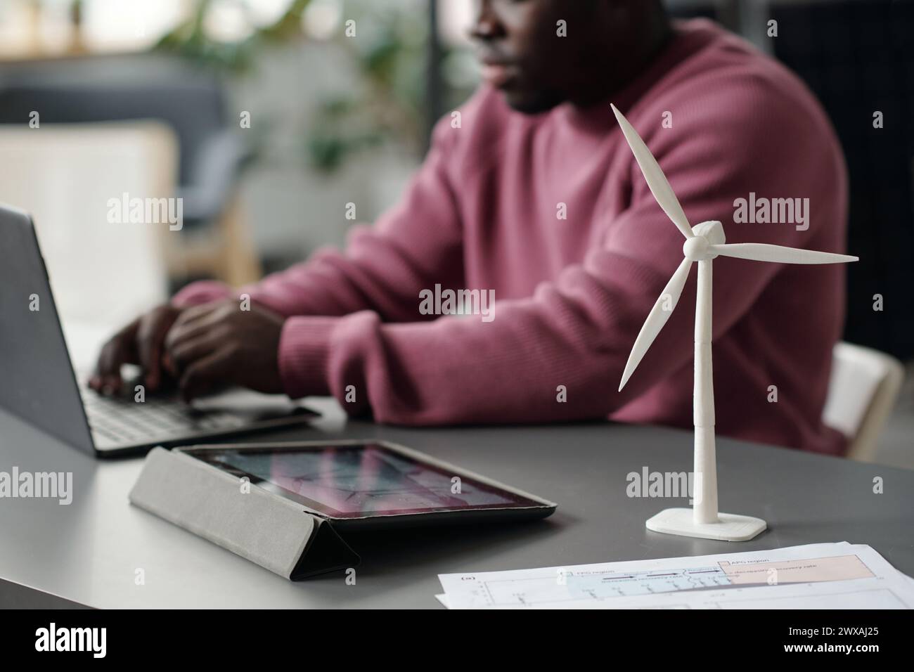Windmill model standing on grey desk next to digital tablet and young ...
