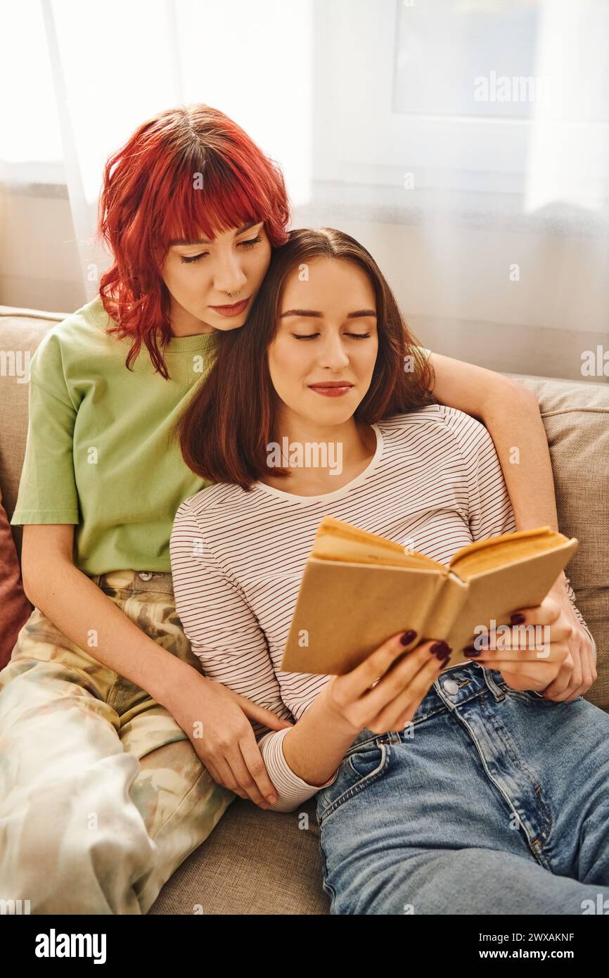 pleased lgbt couple enjoying quiet moment of reading together, wrapped ...
