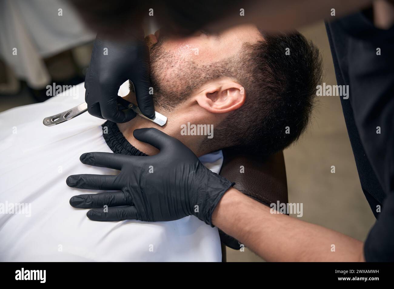Barber trimming man's beard in barbershop Stock Photo - Alamy
