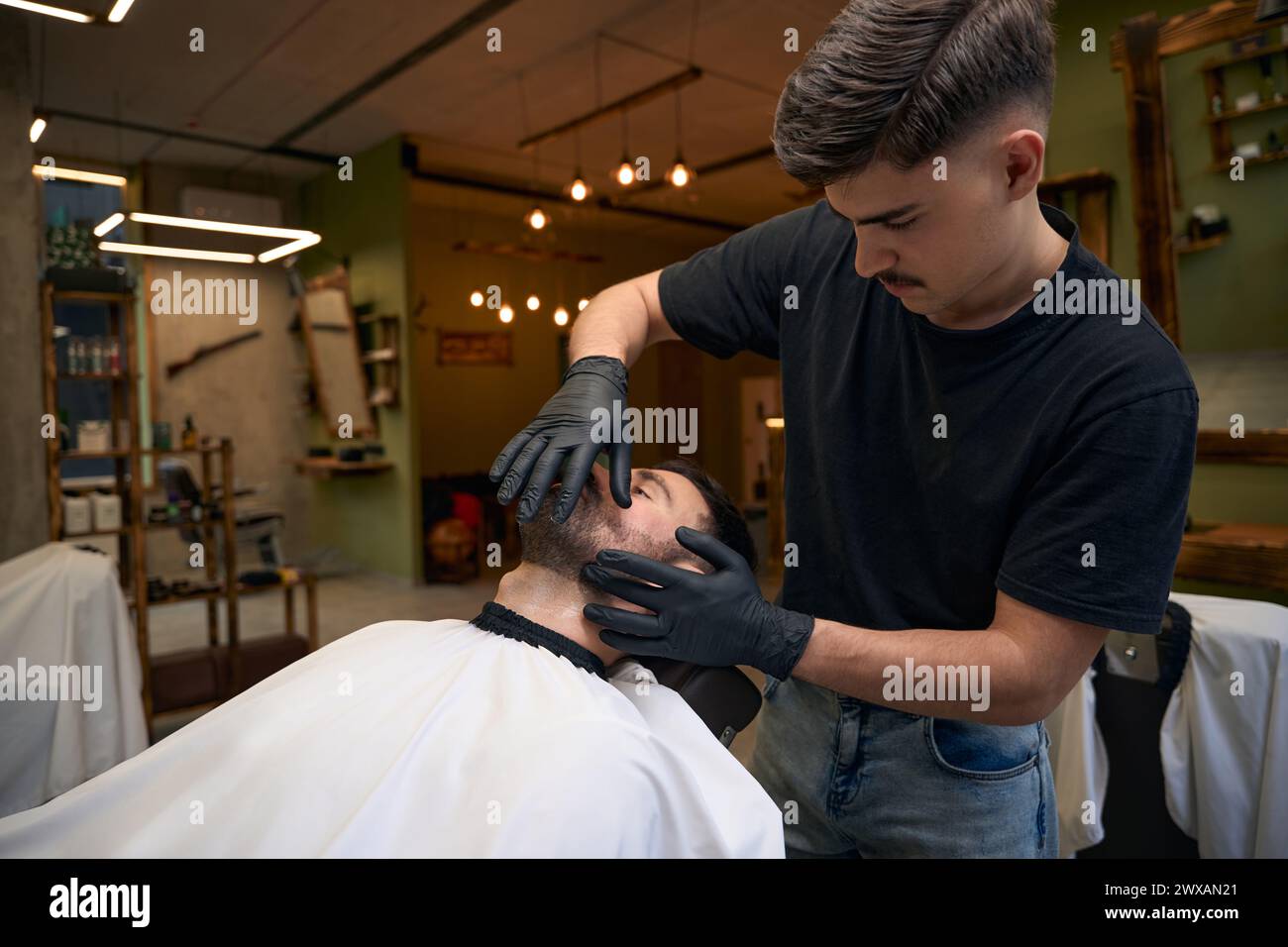 Bearded man getting shaved with straight edge razor by hairdresser ...