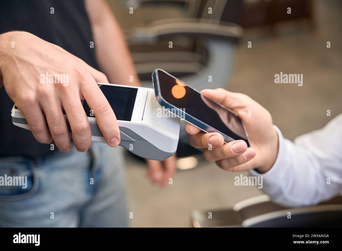 Male client making contactless paying with smartphone on pos terminal ...