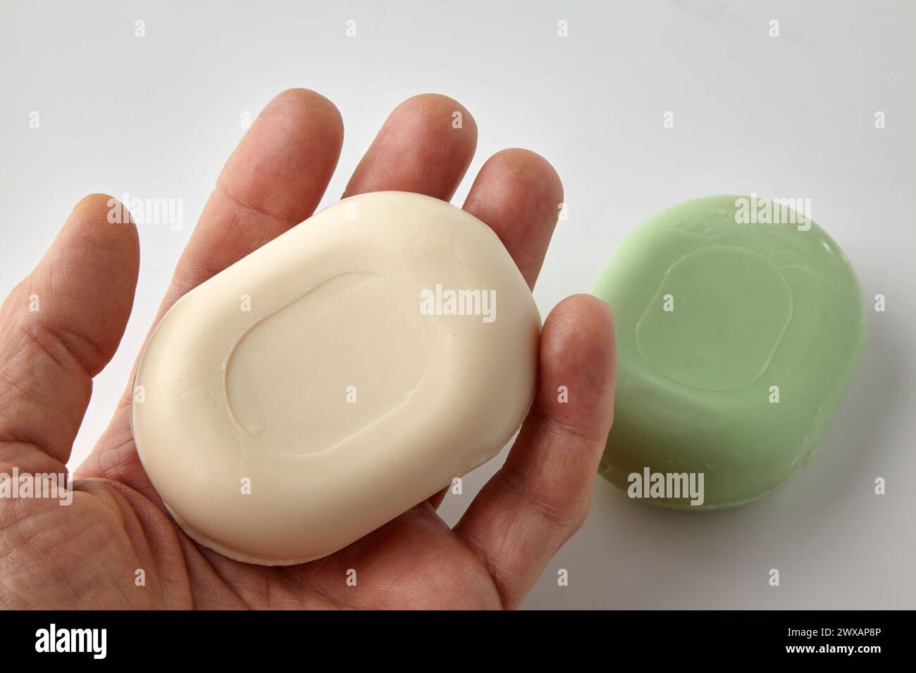 The body part is a hand with a bar of hard soap on a white background ...