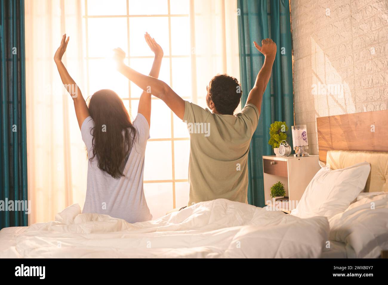 Back view shot of couples stretching hands after waking up from bed by ...