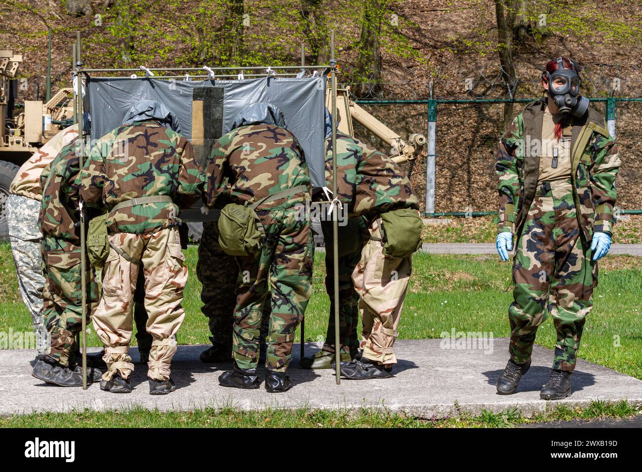 A group of soldiers are standing around a tent, with one of them ...