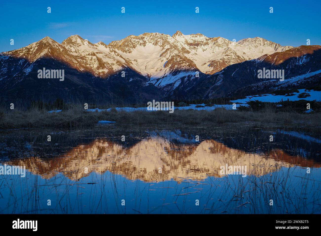 Sunset over the Pyrenees mountains with the reflection of the peaks in ...