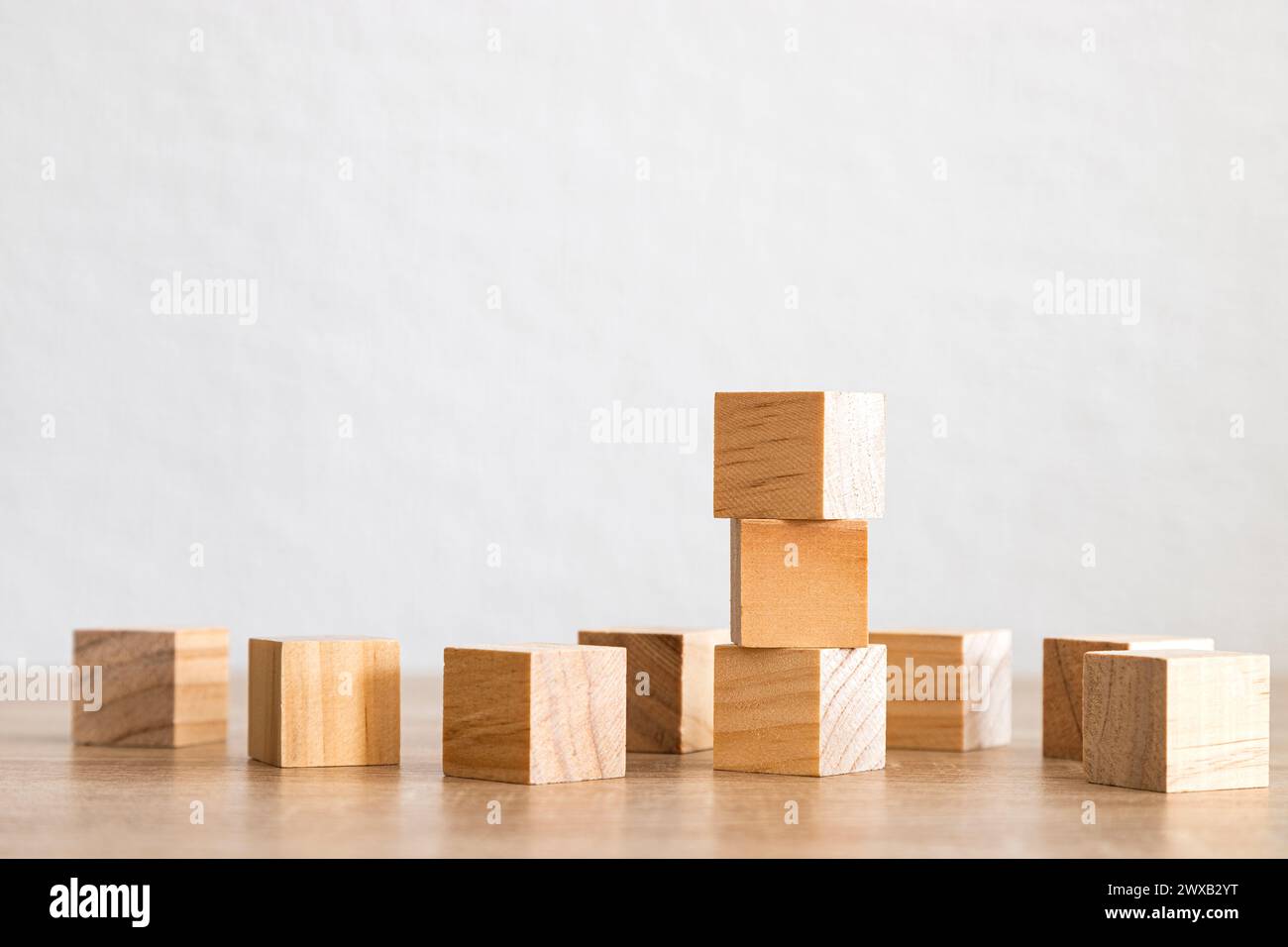 A stacked tower of wooden cubes among scattered blocks on a smooth ...