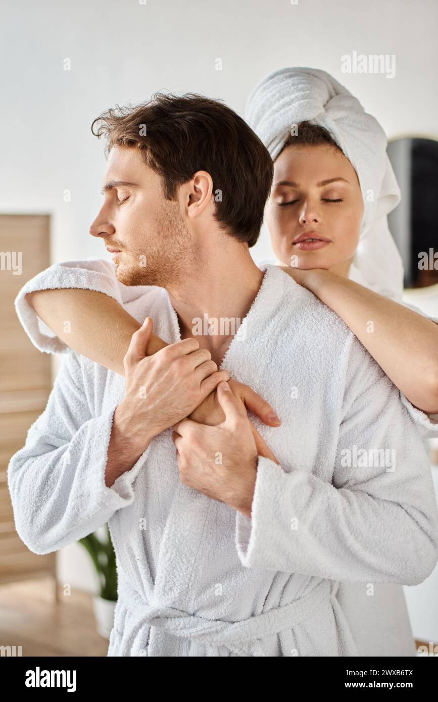 Attractive couple in bathrobes hugging in the bathroom, woman with ...