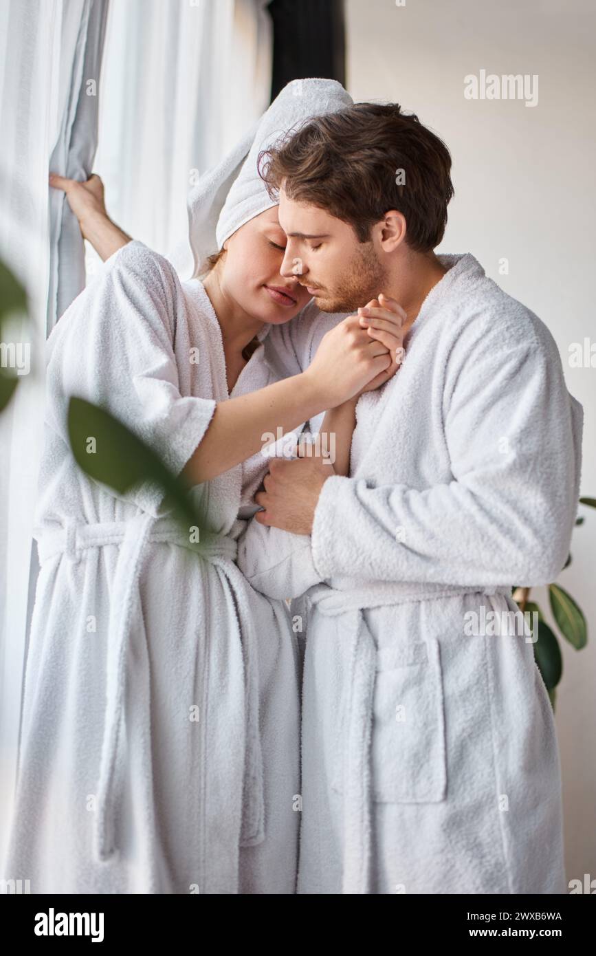 Couple in love wearing bathrobes hugging each other and having loving ...