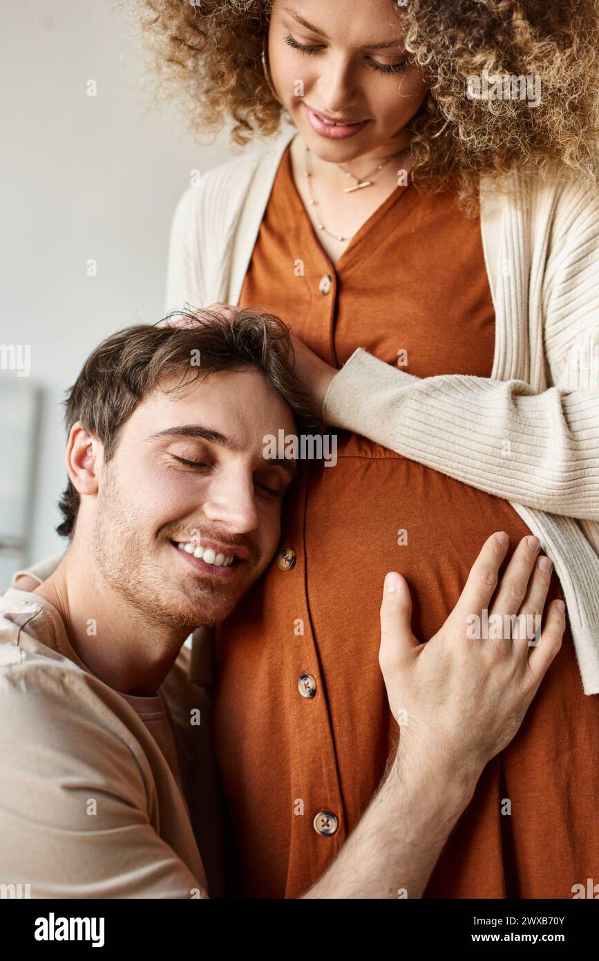 Emotional moment of happy man listening to baby hugging tummy of wife ...