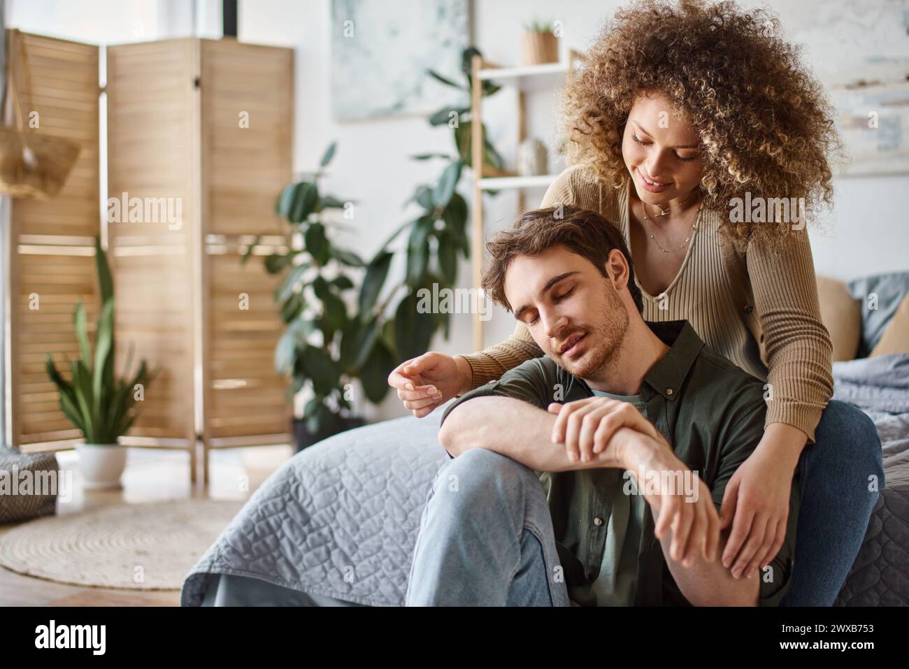 Pretty caring woman hugging her relaxed boyfriend from behind sitting ...