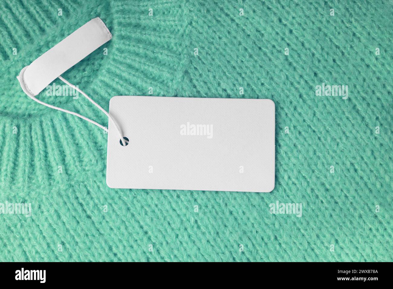 Blank clothing tag and inner label on neck of green knitted sweater ...