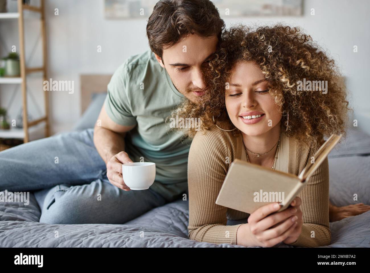 Morning cuddles and book time for curly young woman as brunette man ...