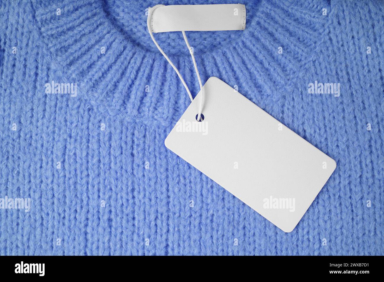 Blank clothing tag and inner label on neck of blue knitted sweater ...