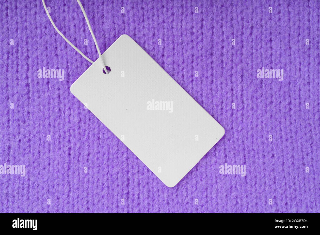 Blank clothing label on purple knitted sweater background. Mockup ...