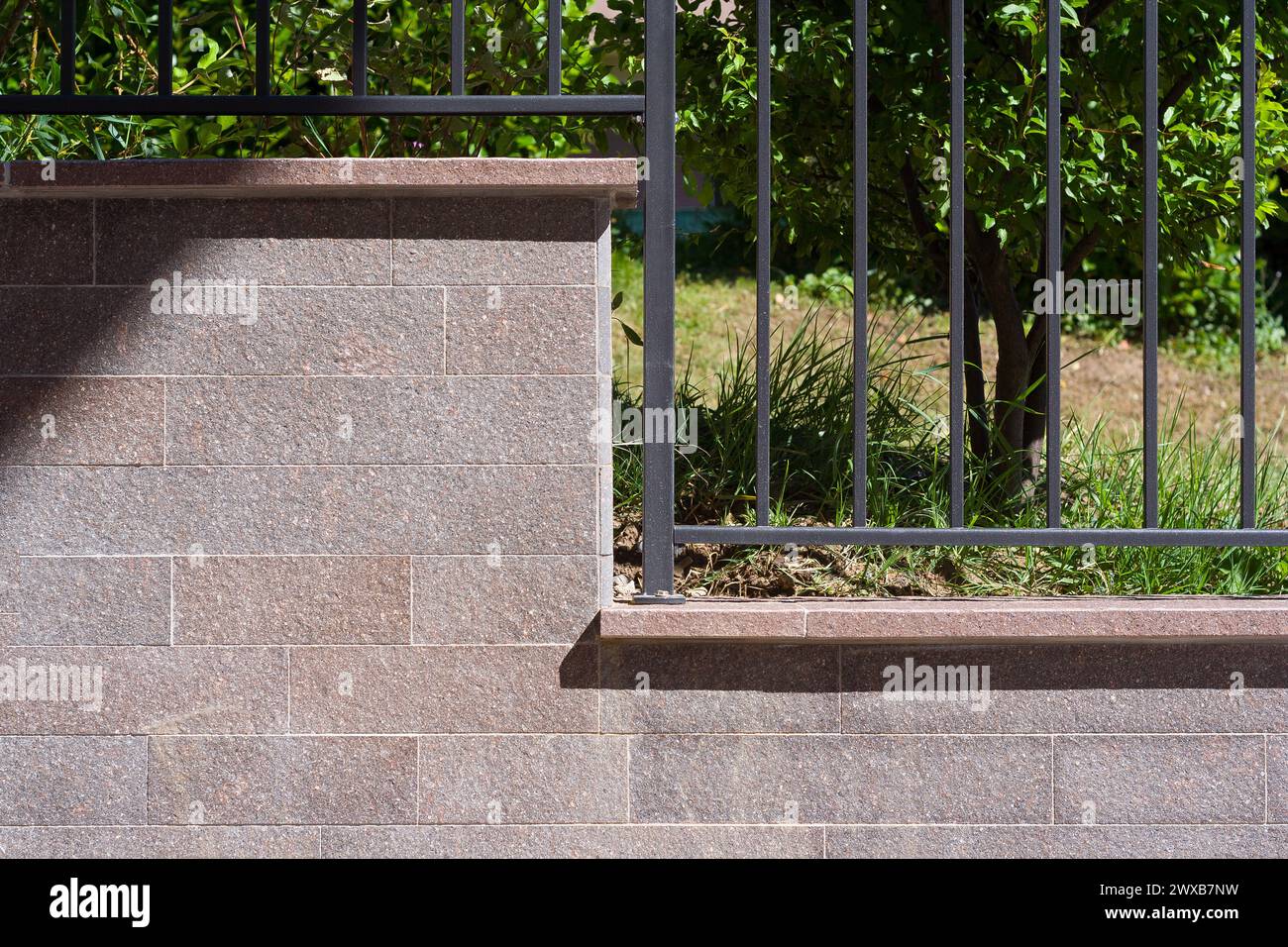 Detail of a porphyry stone wall with metal railing under sunlight ...