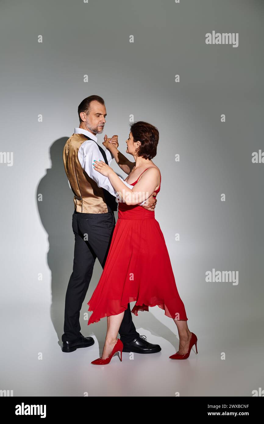 Ballroom dance middle aged couple in red dress and suit dancing tango ...