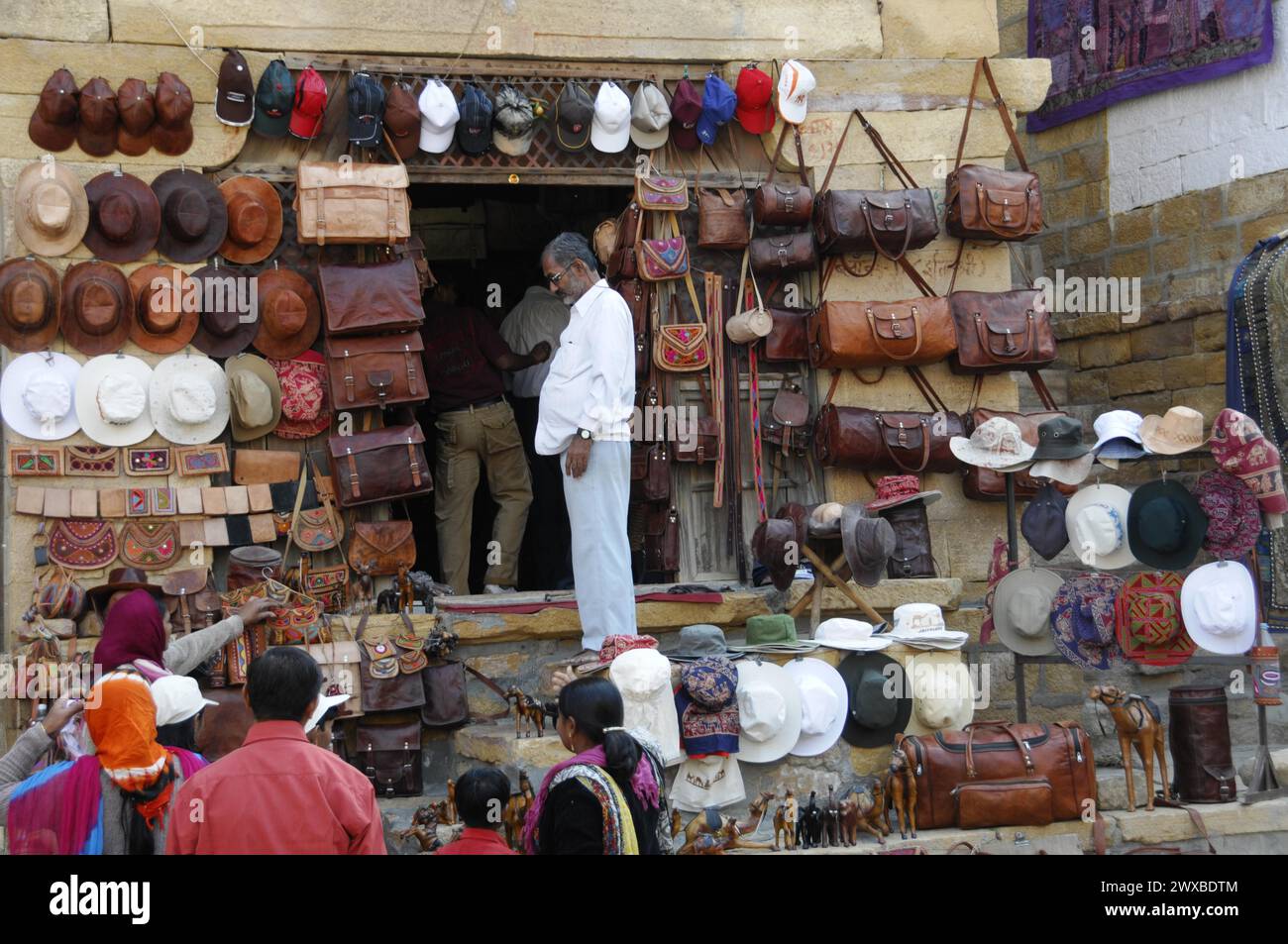 Market stall with a selection of leather hats and bags and a merchant ...
