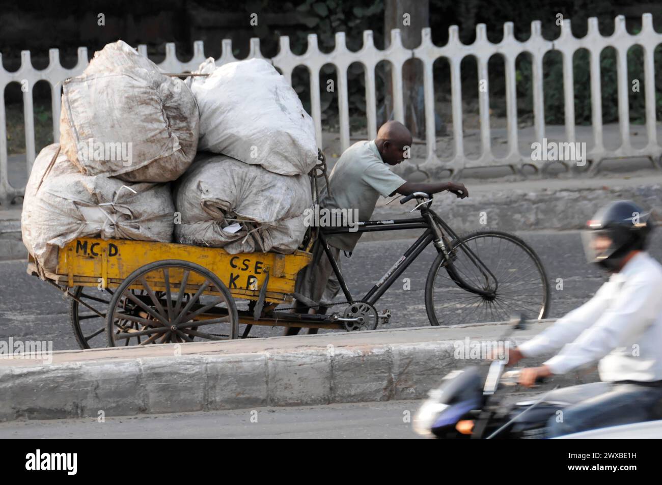 A man pushes a heavily loaded bicycle through traffic, Jaipur ...