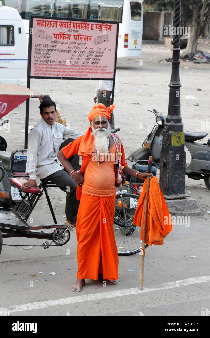 An elderly man in an orange-coloured robe and with a long beard stands ...