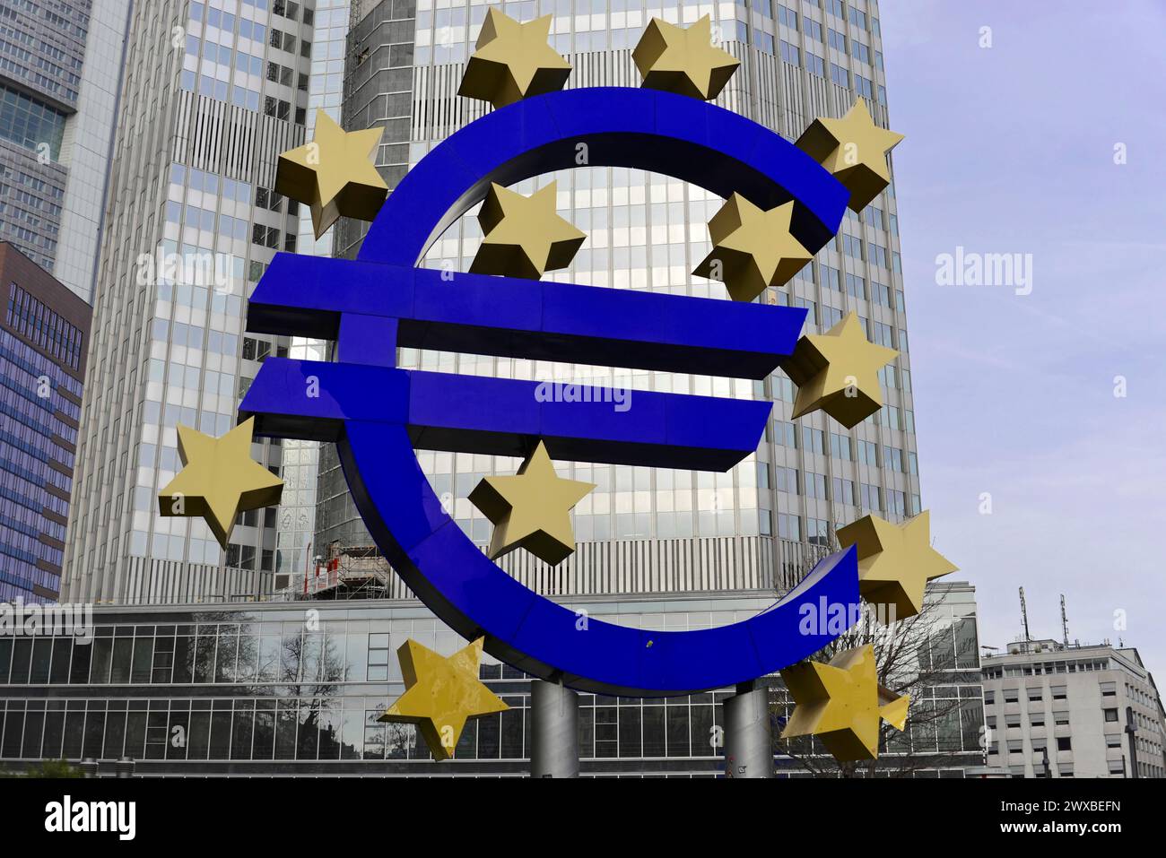 Blue euro sign with golden stars in front of a glass skyscraper on an ...