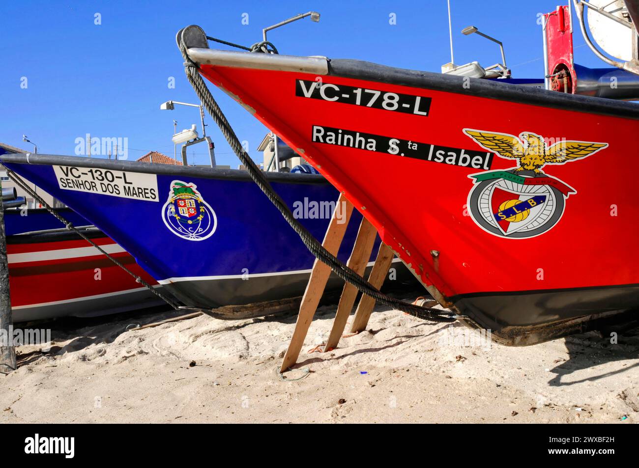 Colourful fishing boats with club emblems lined up on the beach, near ...