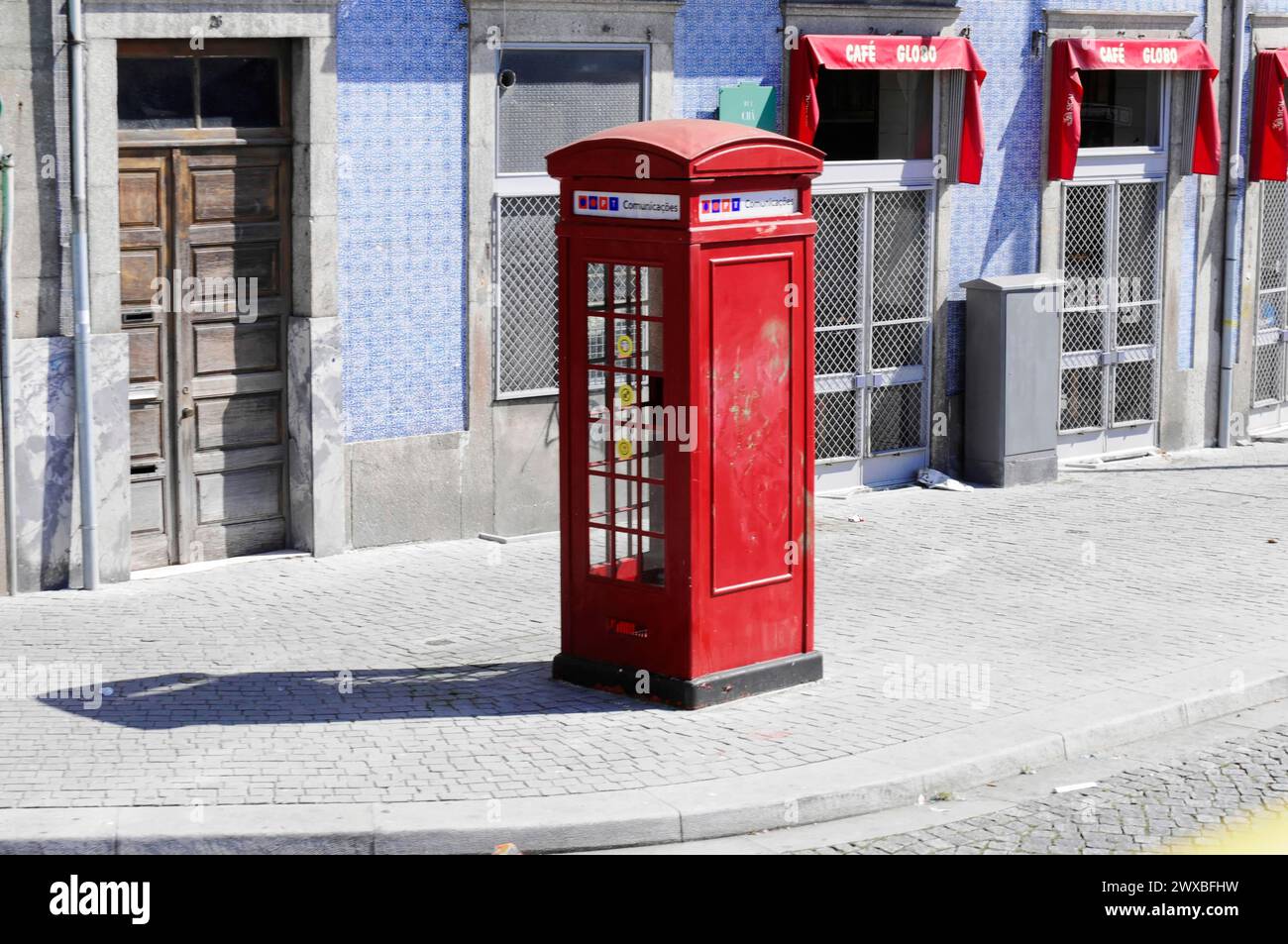 Traditional red telephone box on a cobbled pavement in Portugal ...