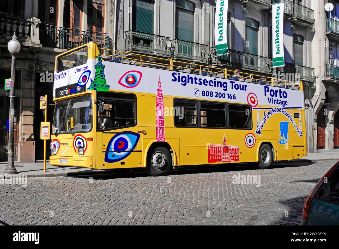 Yellow sightseeing bus on a street in the city of Porto with ...