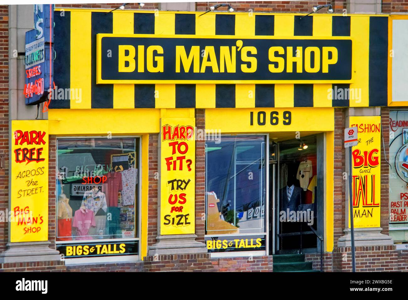 Facade of a plus size shop with eye-catching yellow and black neon sign, Big Man's Shop, retail ...