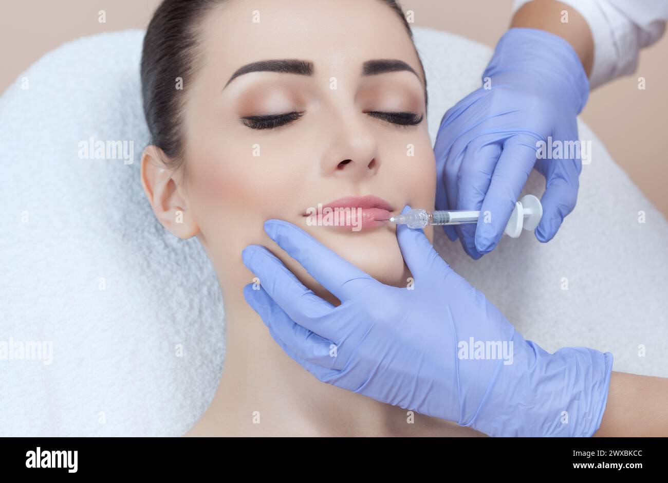 The doctor cosmetologist makes Lip augmentation procedure of a beautiful woman in a beauty salon ...