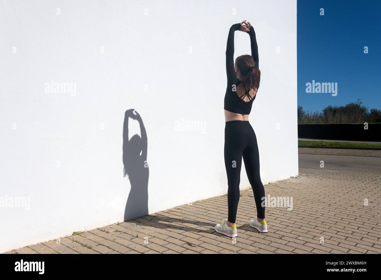 Rear view of a sporty woman doing arm stretching exercises outside in ...
