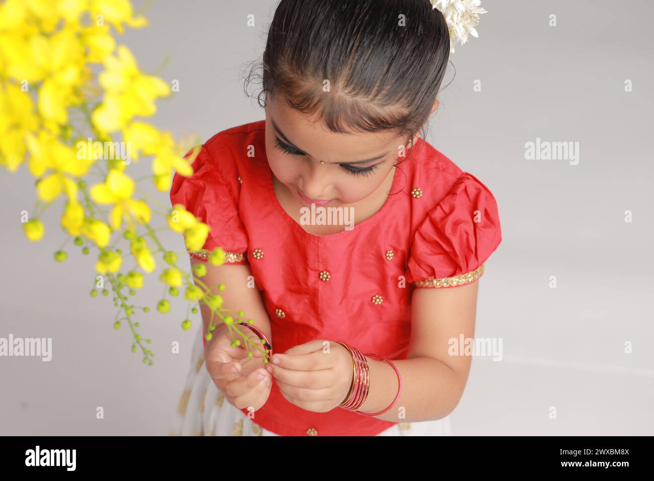 A cute small girl child wearing Kerala dress-golden colour long skirt and red blouse with golden ...