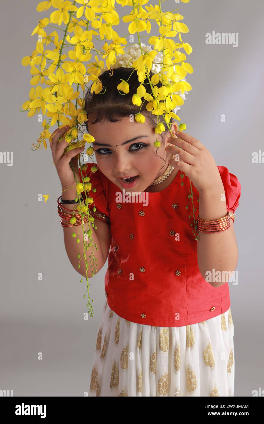 A cute small girl child wearing Kerala dress-golden colour long skirt and red blouse with golden ...