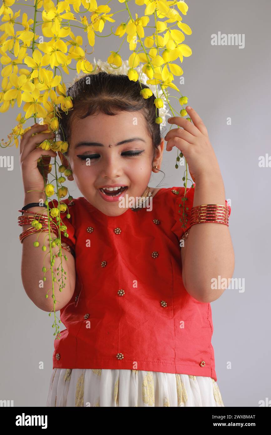 A cute small girl child wearing Kerala dress-golden colour long skirt and red blouse with golden ...