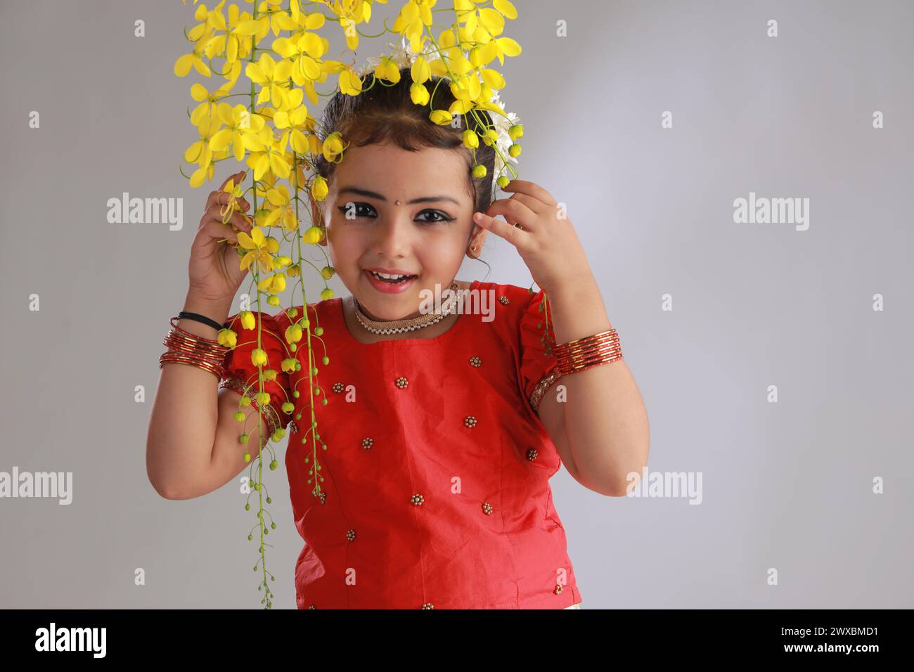 A cute small girl child wearing Kerala dress-golden colour long skirt and red blouse with golden ...