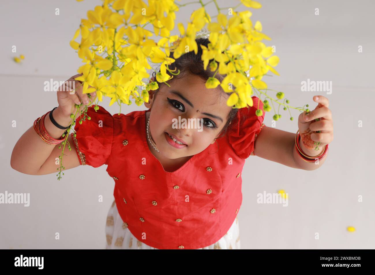 A cute small girl child wearing Kerala dress-golden colour long skirt and red blouse with golden ...