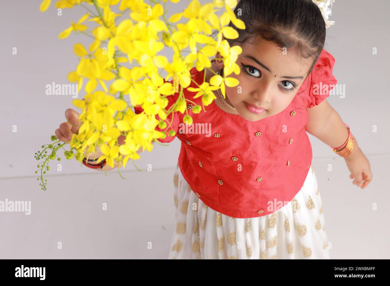 A cute small girl child wearing Kerala dress-golden colour long skirt and red blouse with golden ...