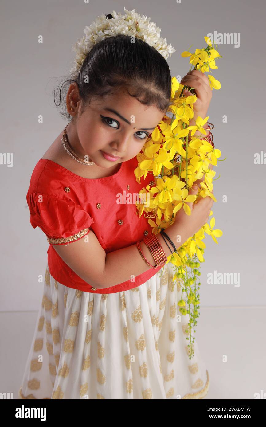 A cute small girl child wearing Kerala dress-golden colour long skirt and red blouse with golden ...