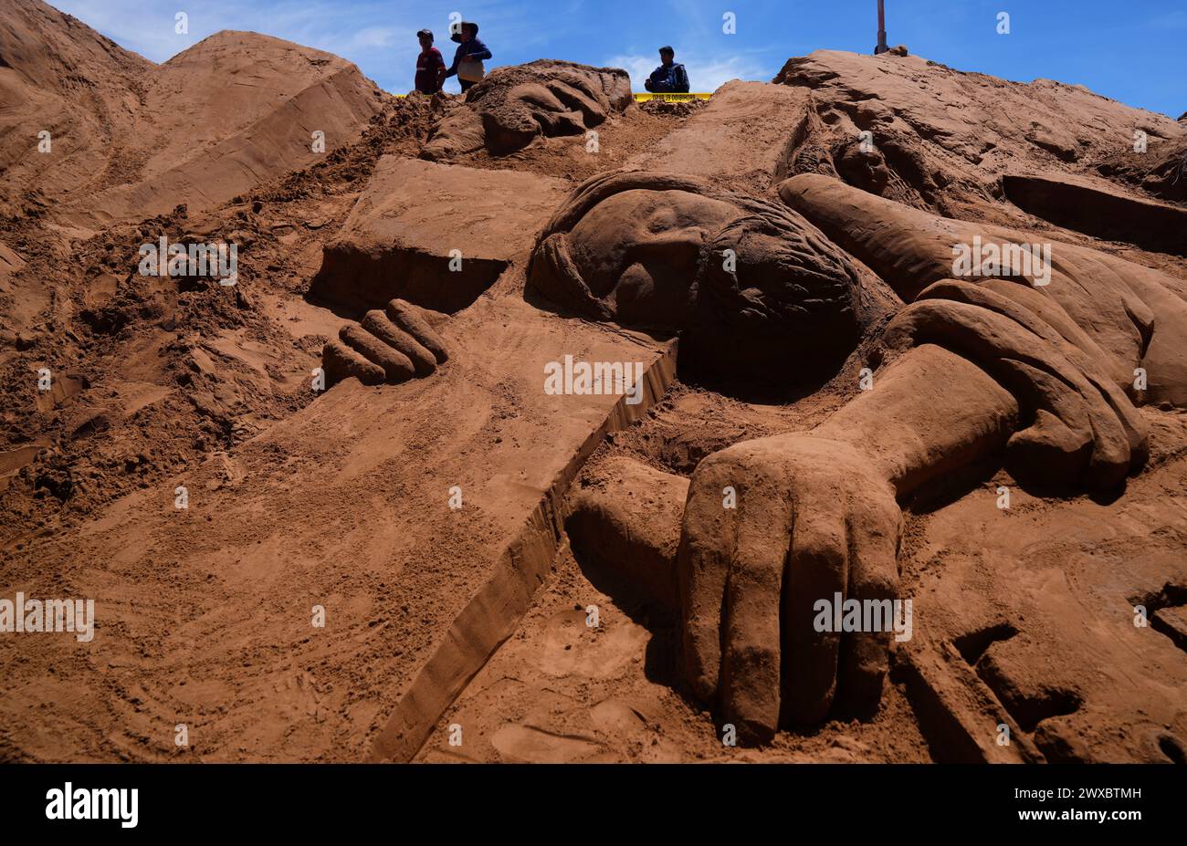 Visitors walk past a sand sculpture depicting Jesus Christ carrying a ...
