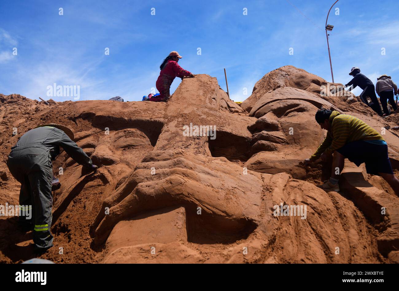 Artists work on a sand sculpture depicting Simon of Cyrene helping ...
