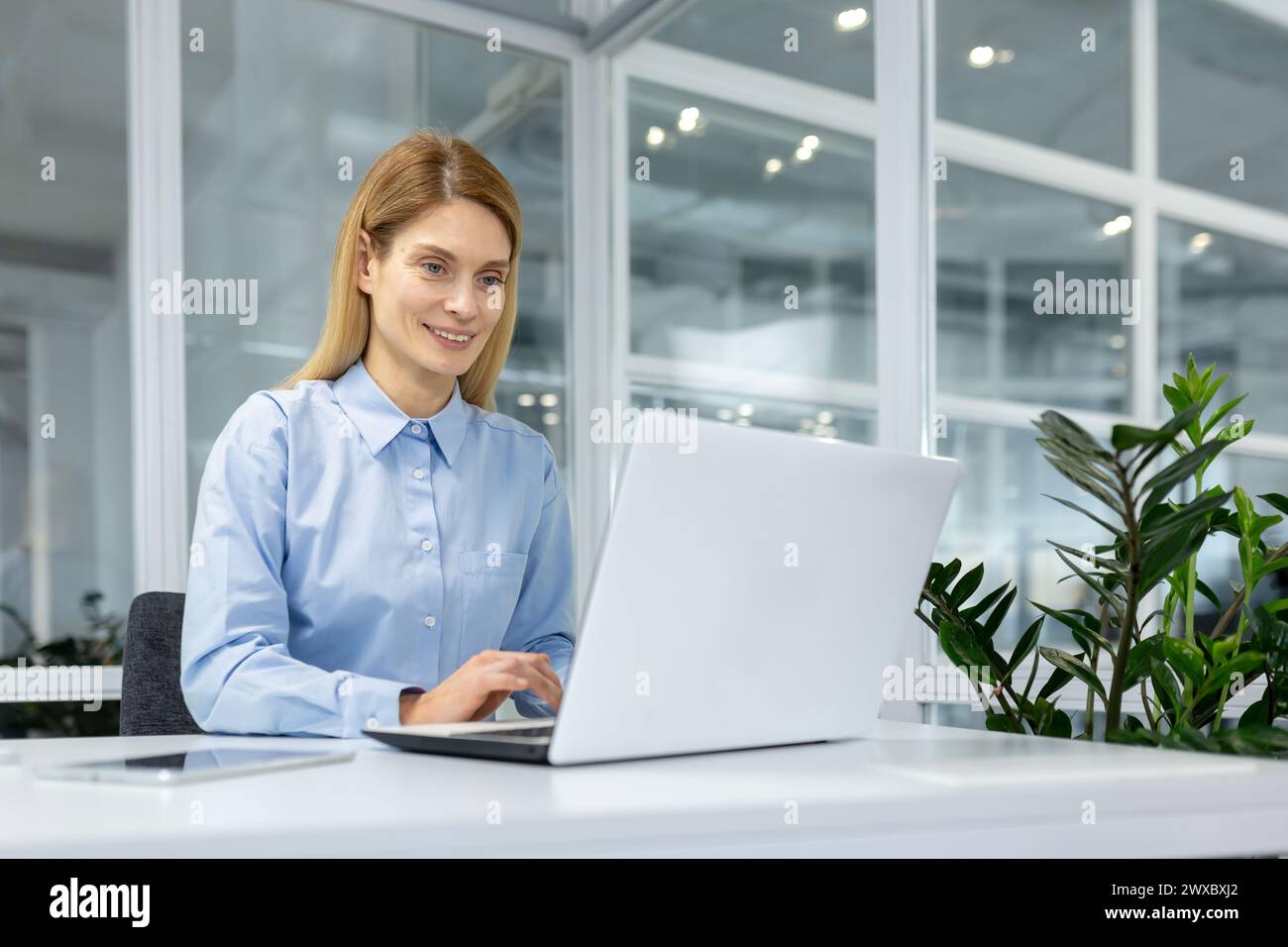 A focused professional woman engages with her laptop in a bright ...