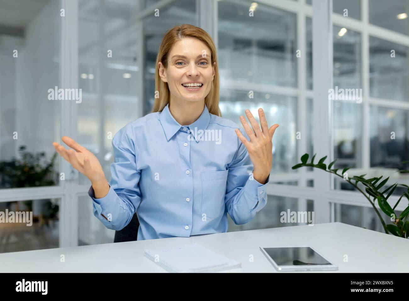 A professional woman in a blue shirt gestures animatedly while looking ...