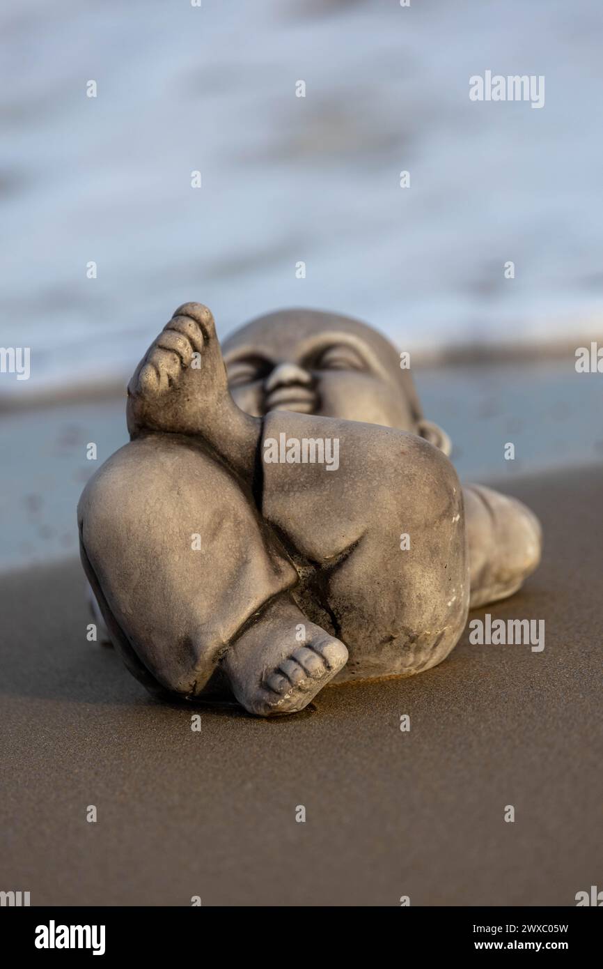 Statue of little Buddha lying on the beach Stock Photo - Alamy
