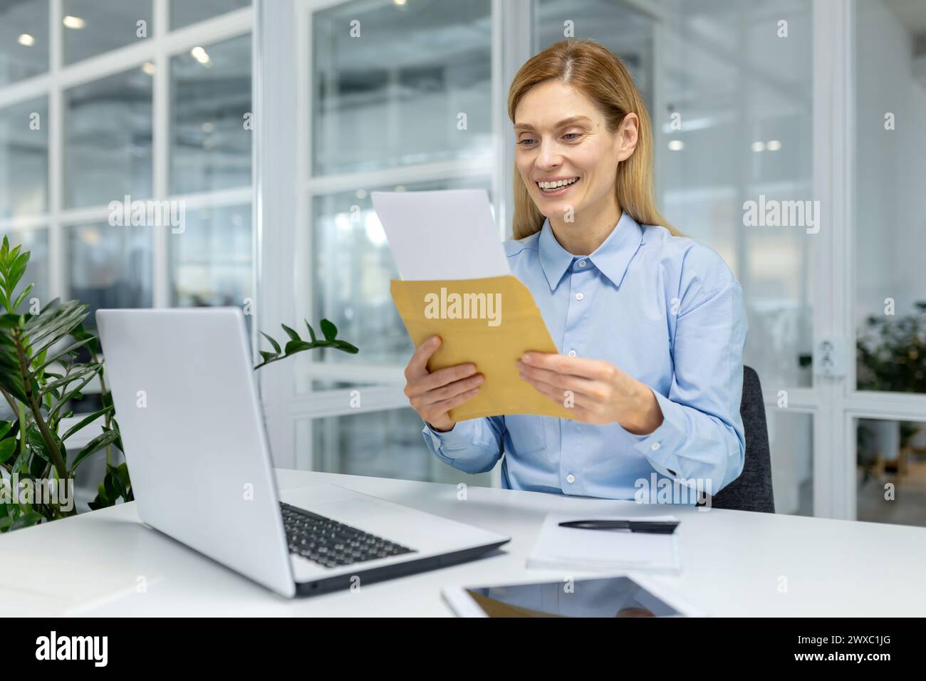 Smiling professional woman reading a letter, expressing joy and ...