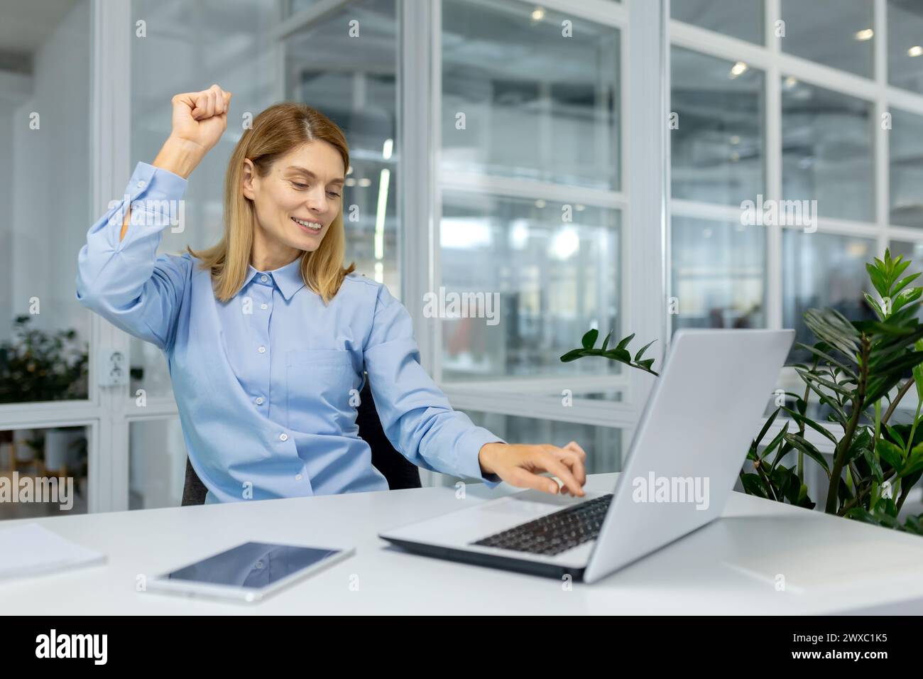 A joyful female employee celebrates success with a dance at her ...