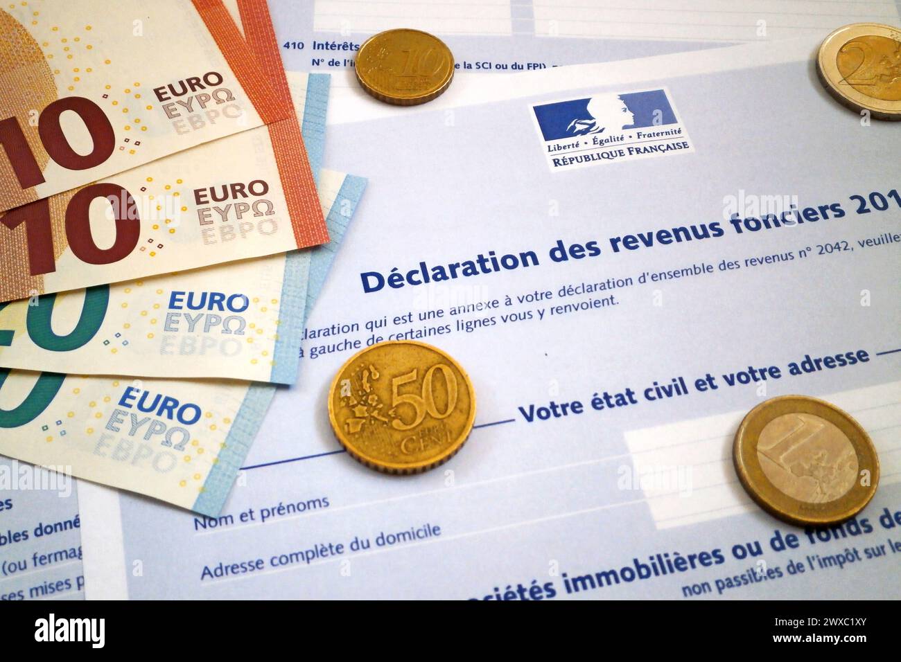 Some euro coins and banknotes on the top of a French property tax form ...