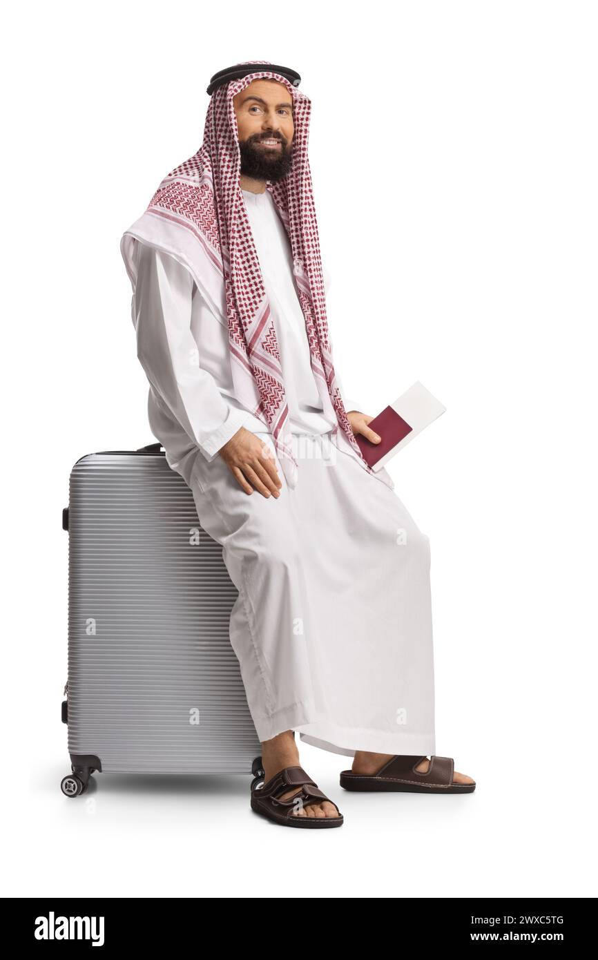Saudi arab man sitting on a suitcase and holding a passport isolated on ...